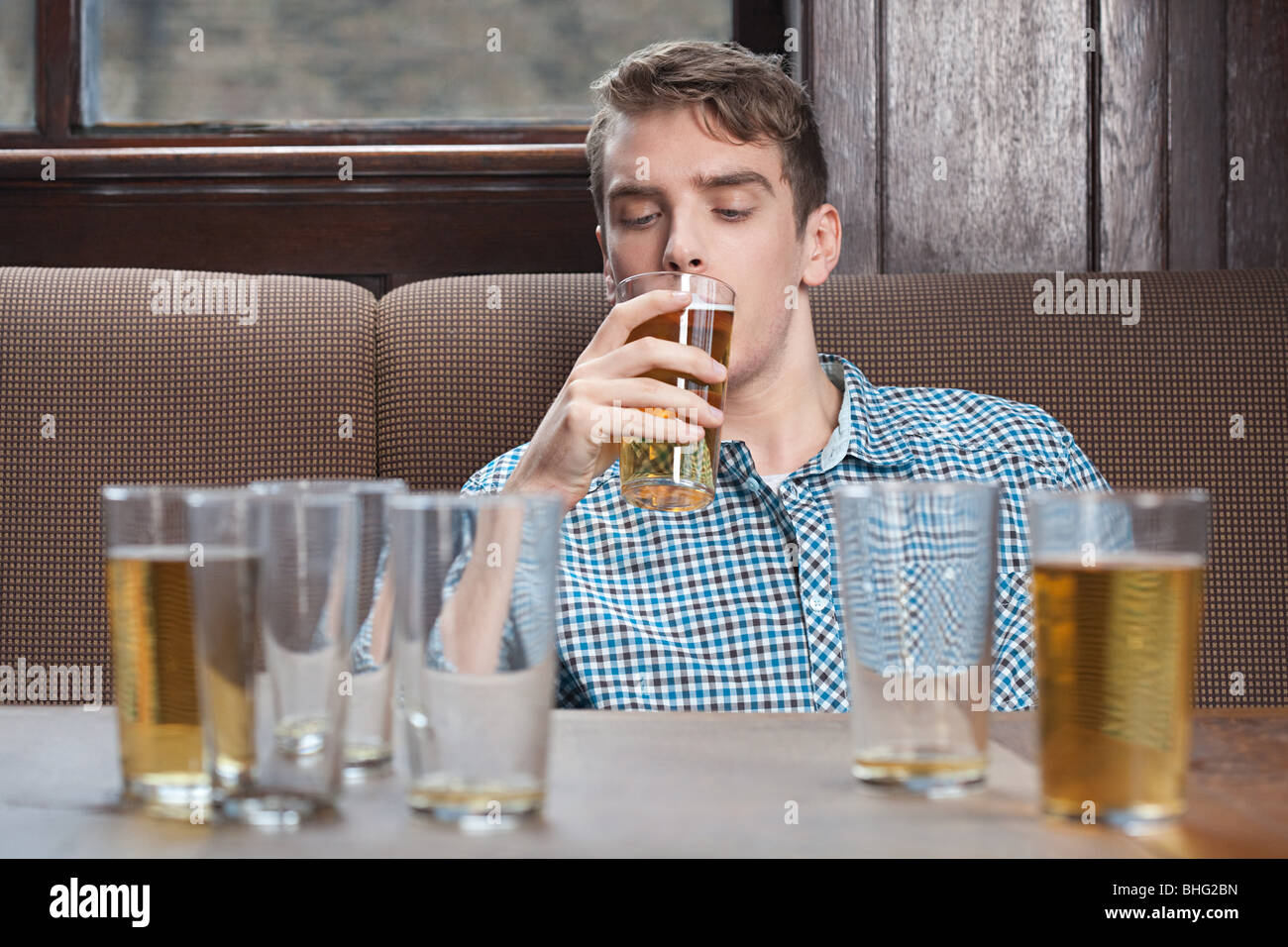 Young man drinking beer in bar Stock Photo - Alamy