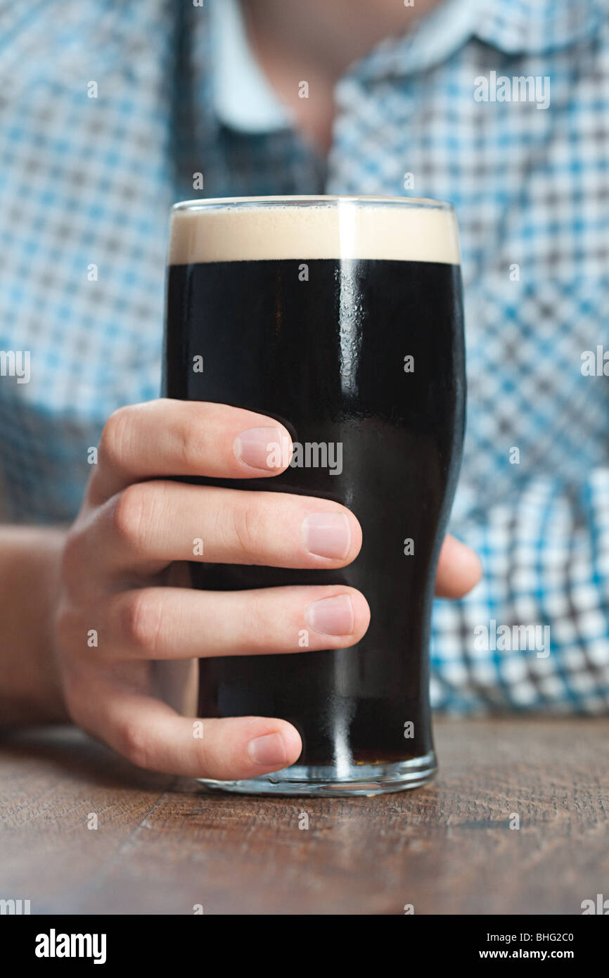 Young man holding pint glass, close up Stock Photo - Alamy
