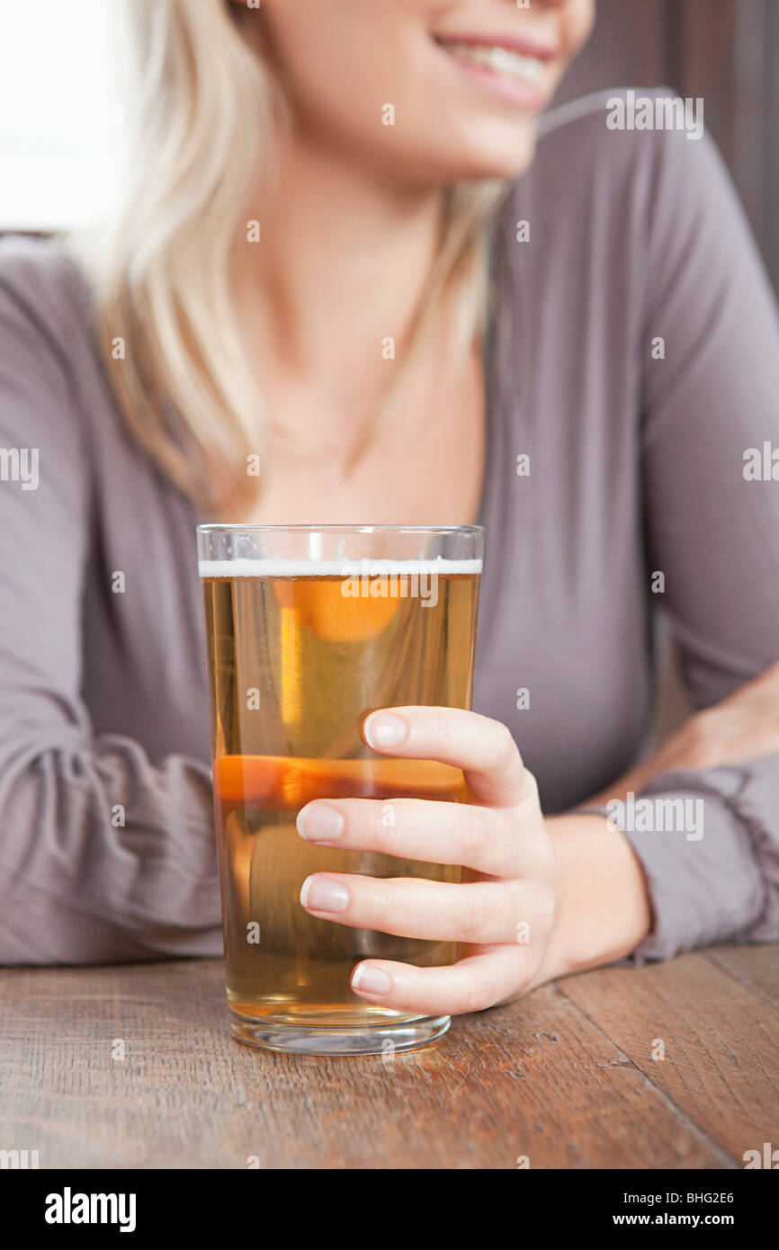 Young woman in bar holding pint of beer Stock Photo - Alamy