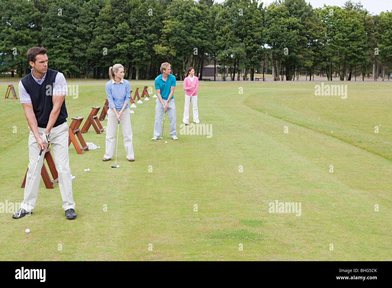 Four golfers on a driving range Stock Photo - Alamy