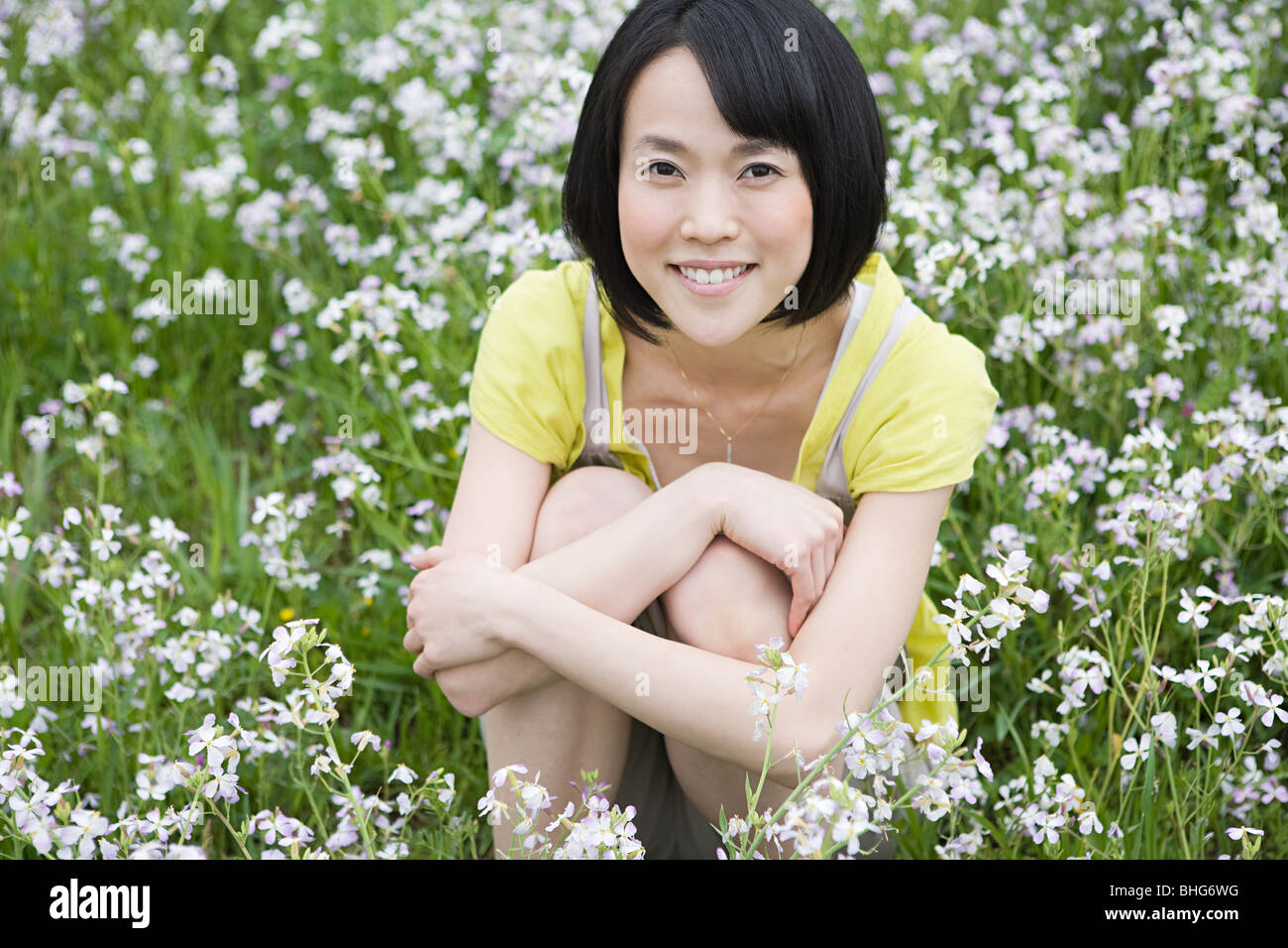 Young woman sitting in field of flowers Stock Photo - Alamy