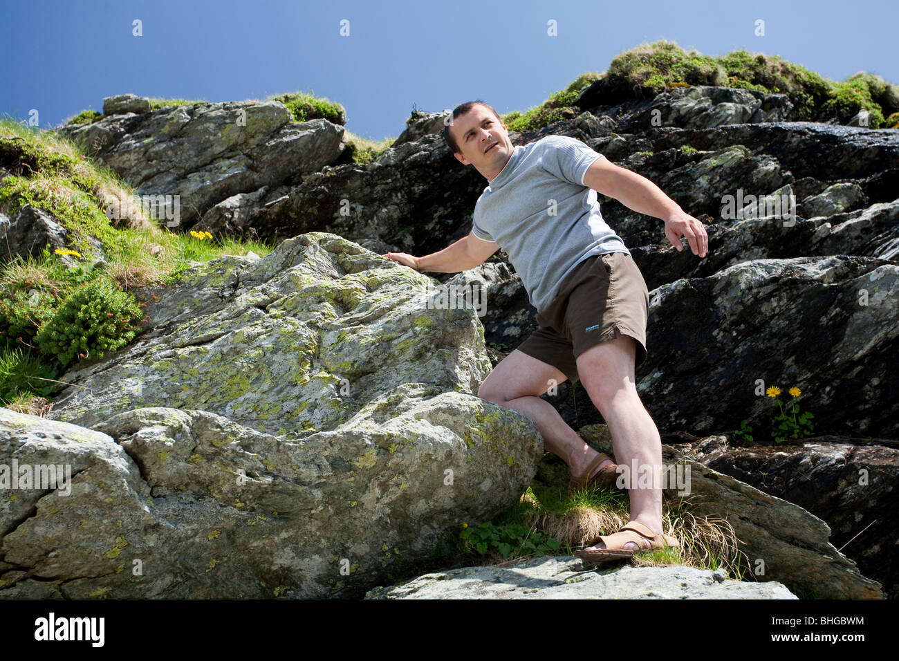 Strong man climbing rocky mountain Stock Photo - Alamy