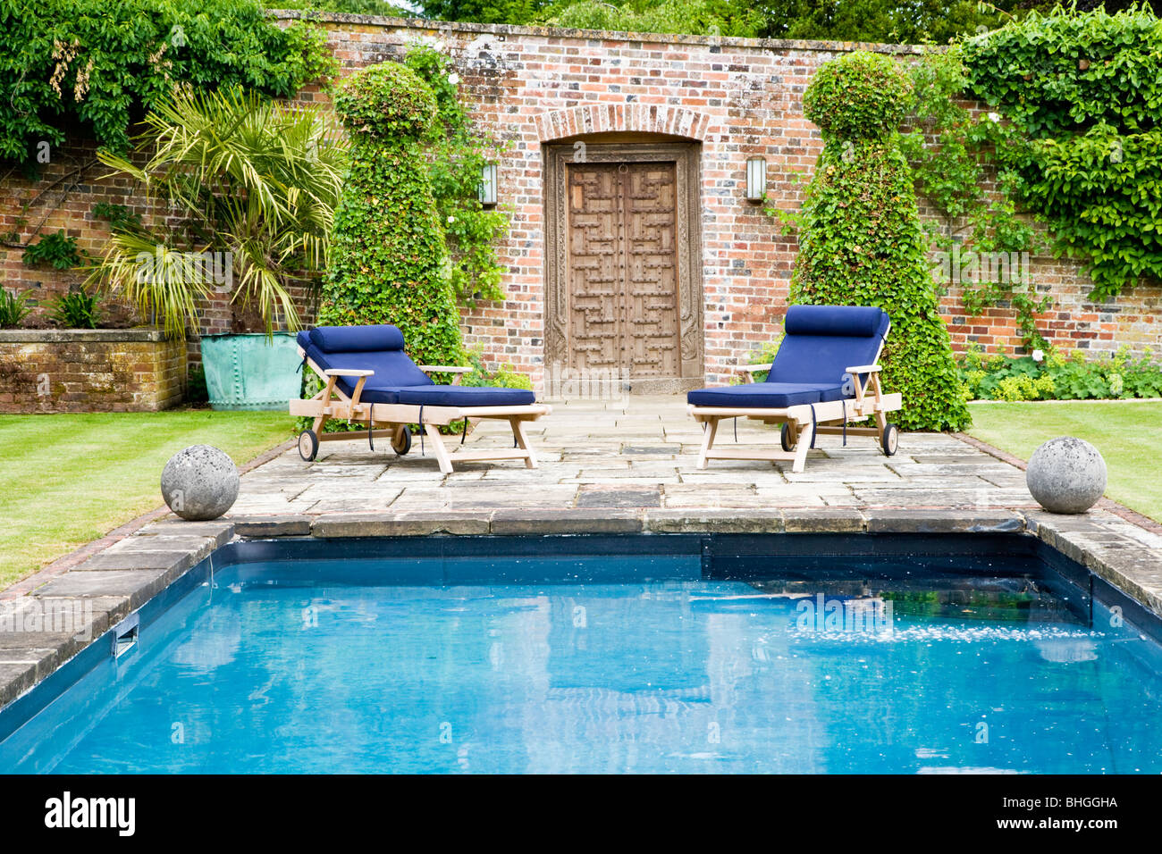 Swimming pool and sunloungers in a walled garden in the grounds of an ...