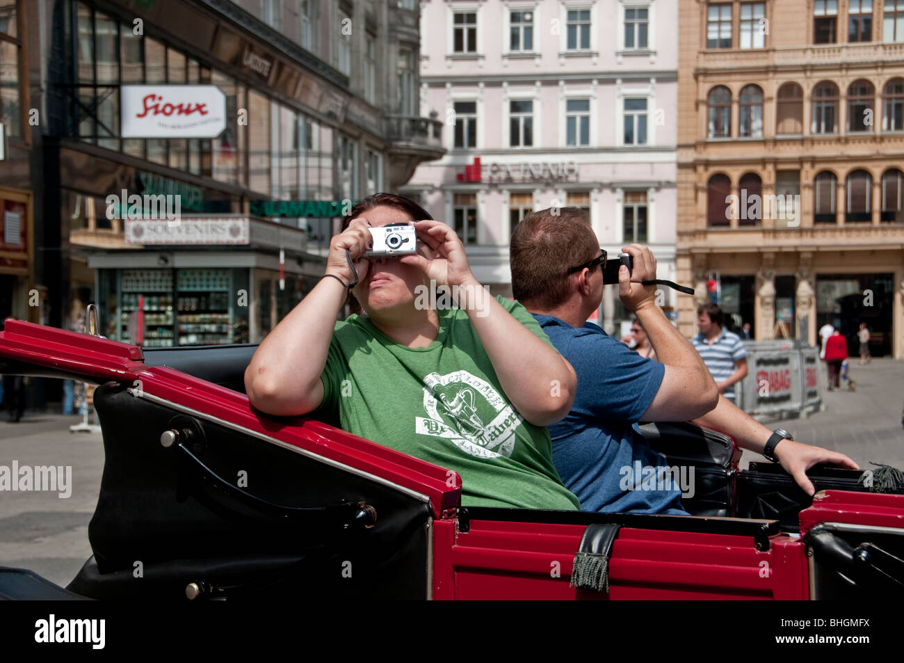 Tourists with cameras riding in a Viennese Fiaker horse carriage in ...