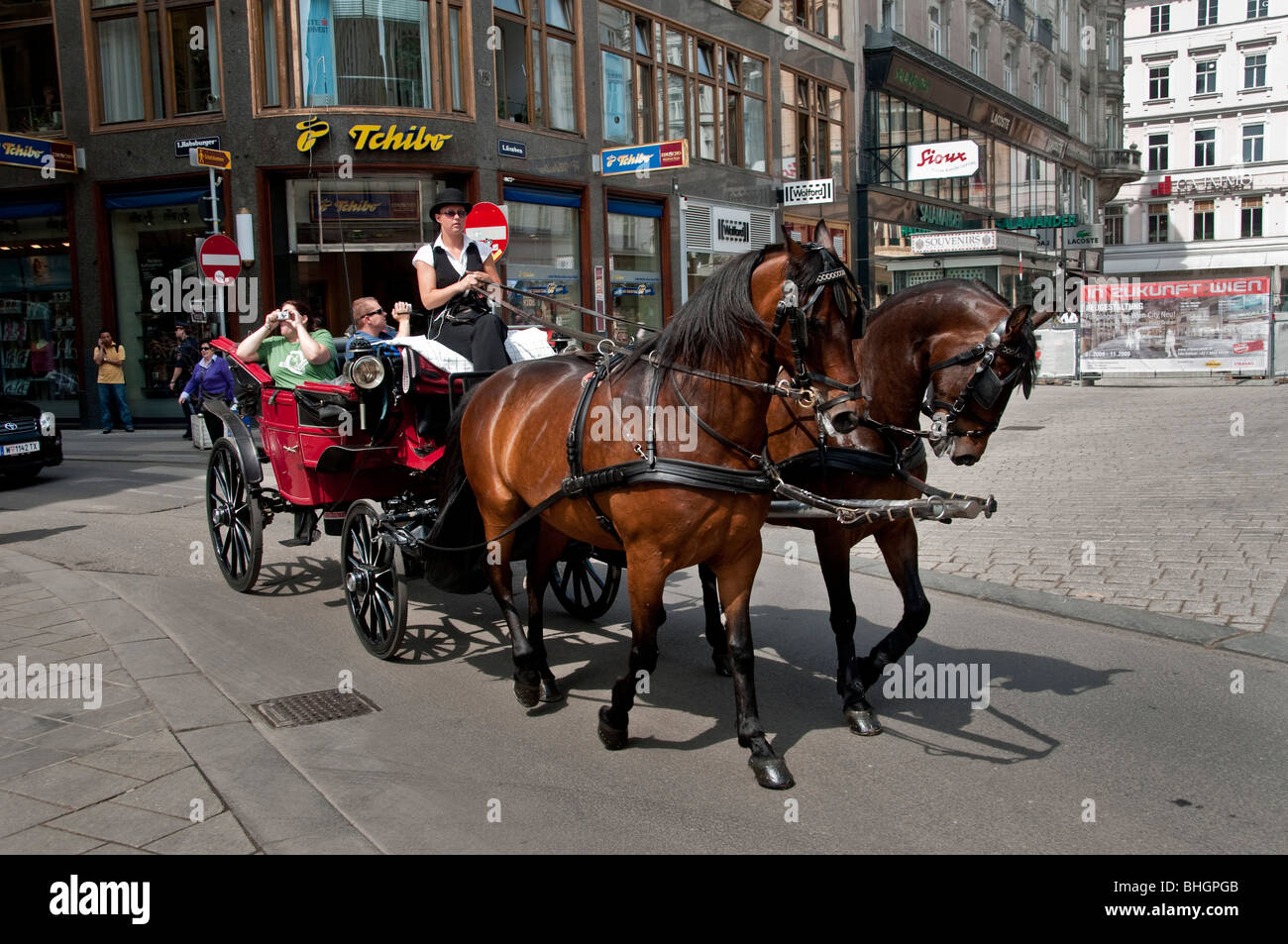 Tourists with cameras riding in a Viennese Fiaker horse carriage in ...