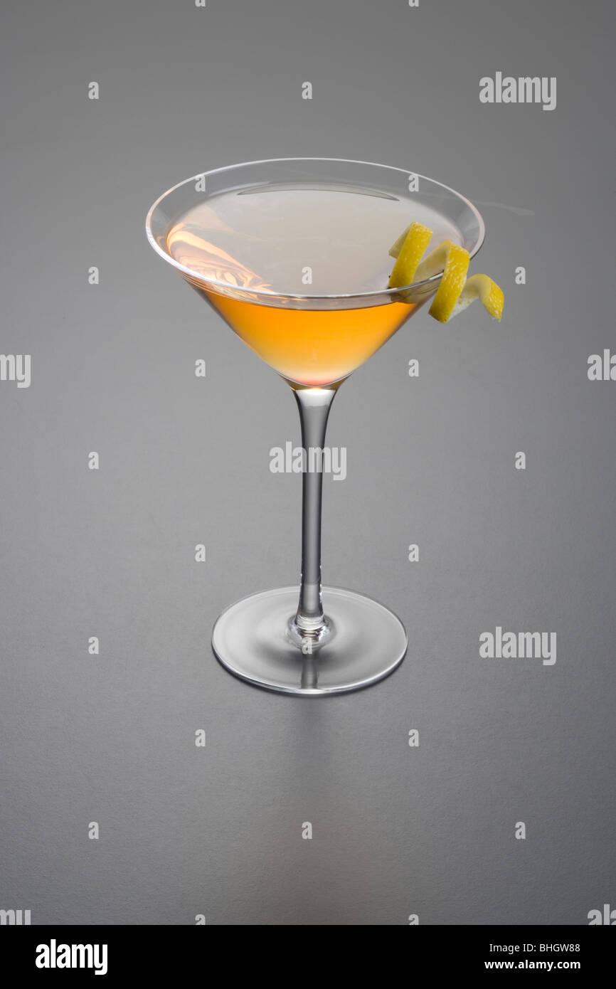 Dry Manhattan cocktail with lemon peel garnish close up on gray ...