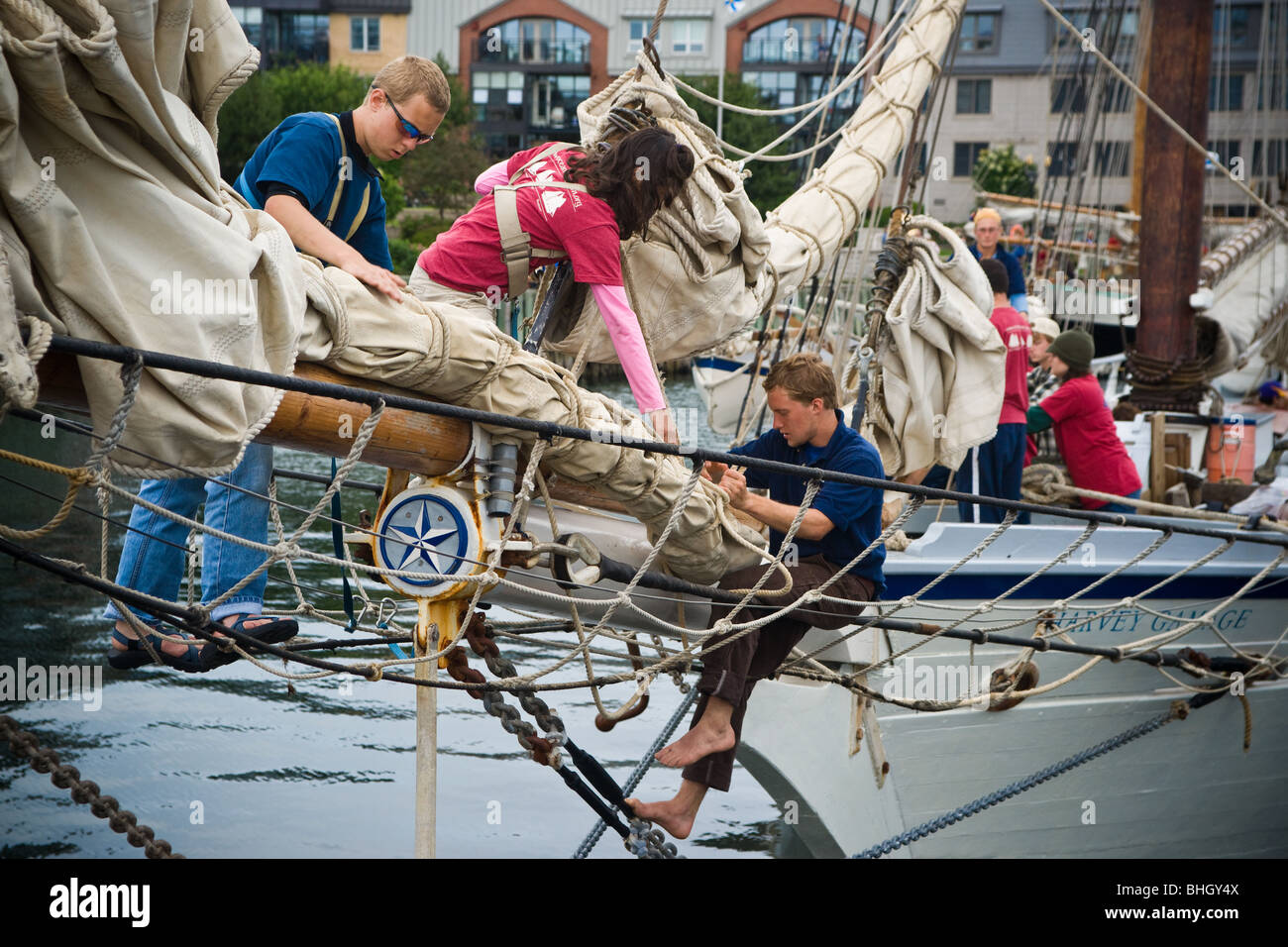 Young trainees furl a sail on the bowsprit of the schooner Harvey ...
