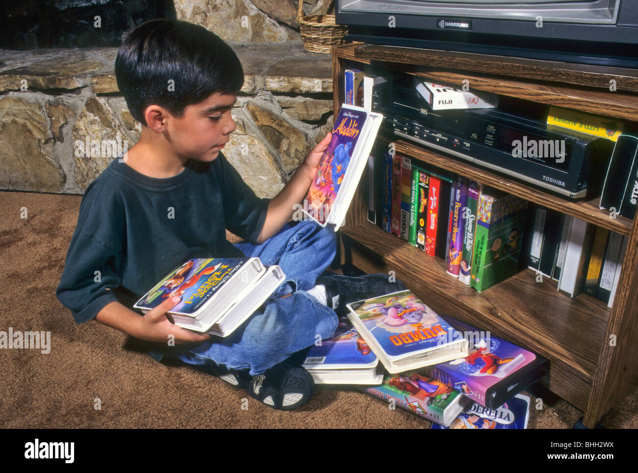 young Hispanic boy male kid select choose VCR video tape movie show TV ...