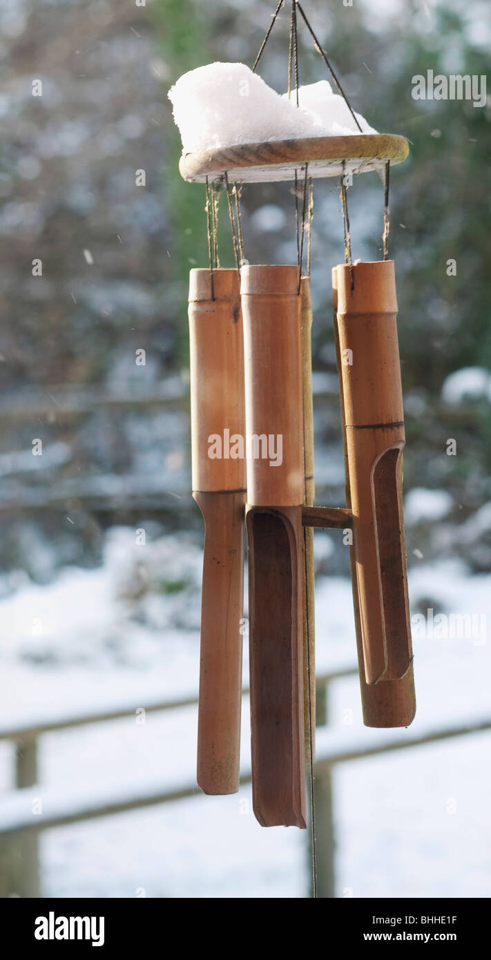 bamboo wind chimes hanging from roof in garden in winter with snow ...