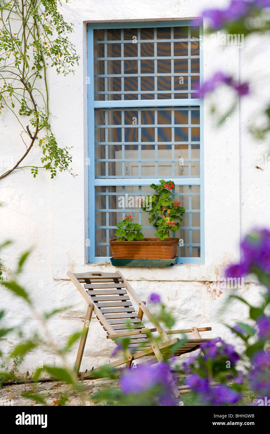Wooden deckchair beneath window Stock Photo - Alamy