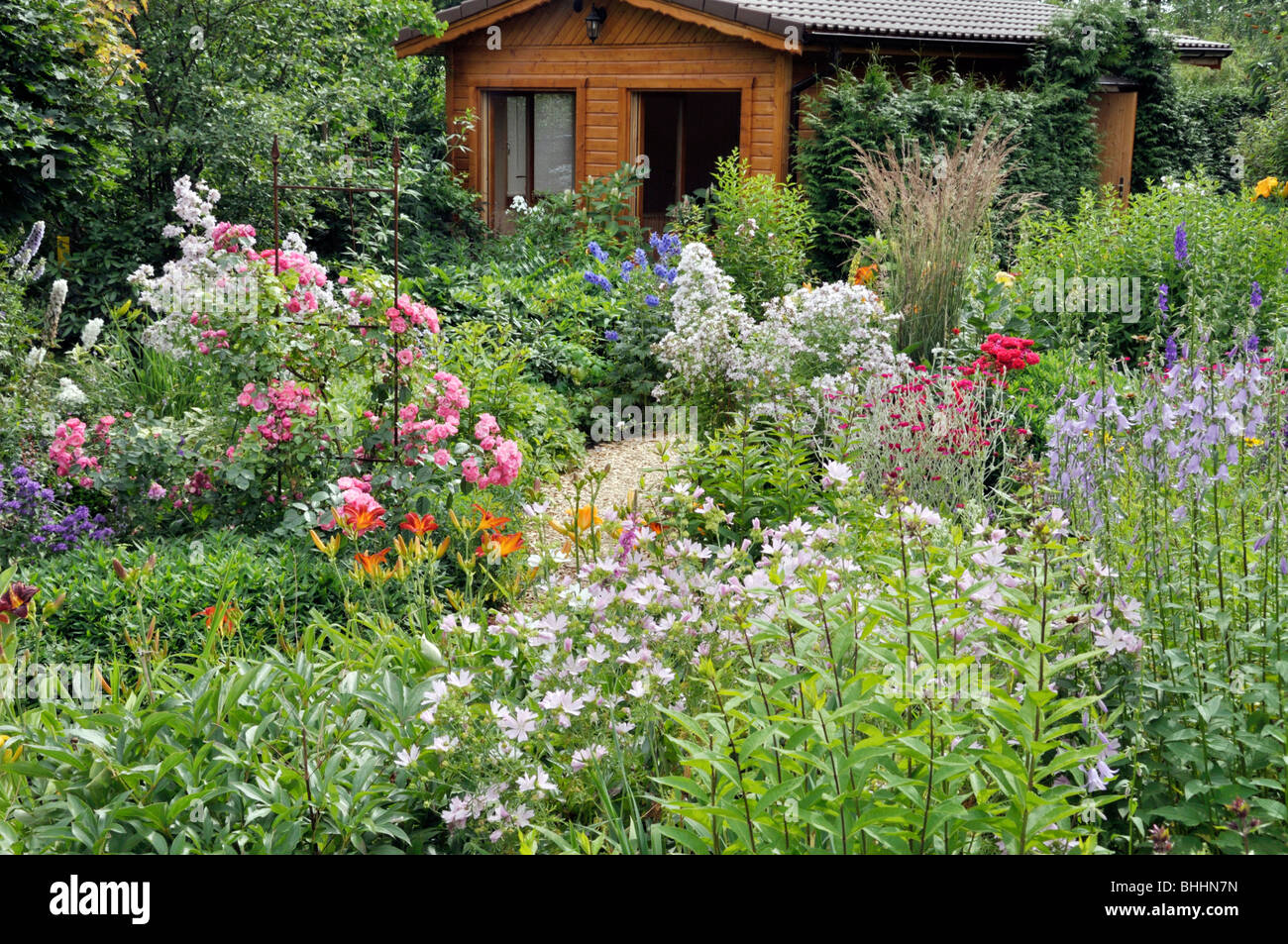 Wooden house in a rich flowering garden. Design: Marianne and Detlef ...