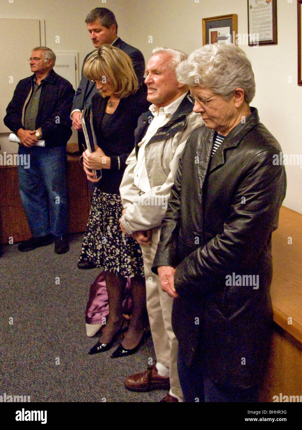 Local citizens bow their heads in prayer at the opening of a city ...