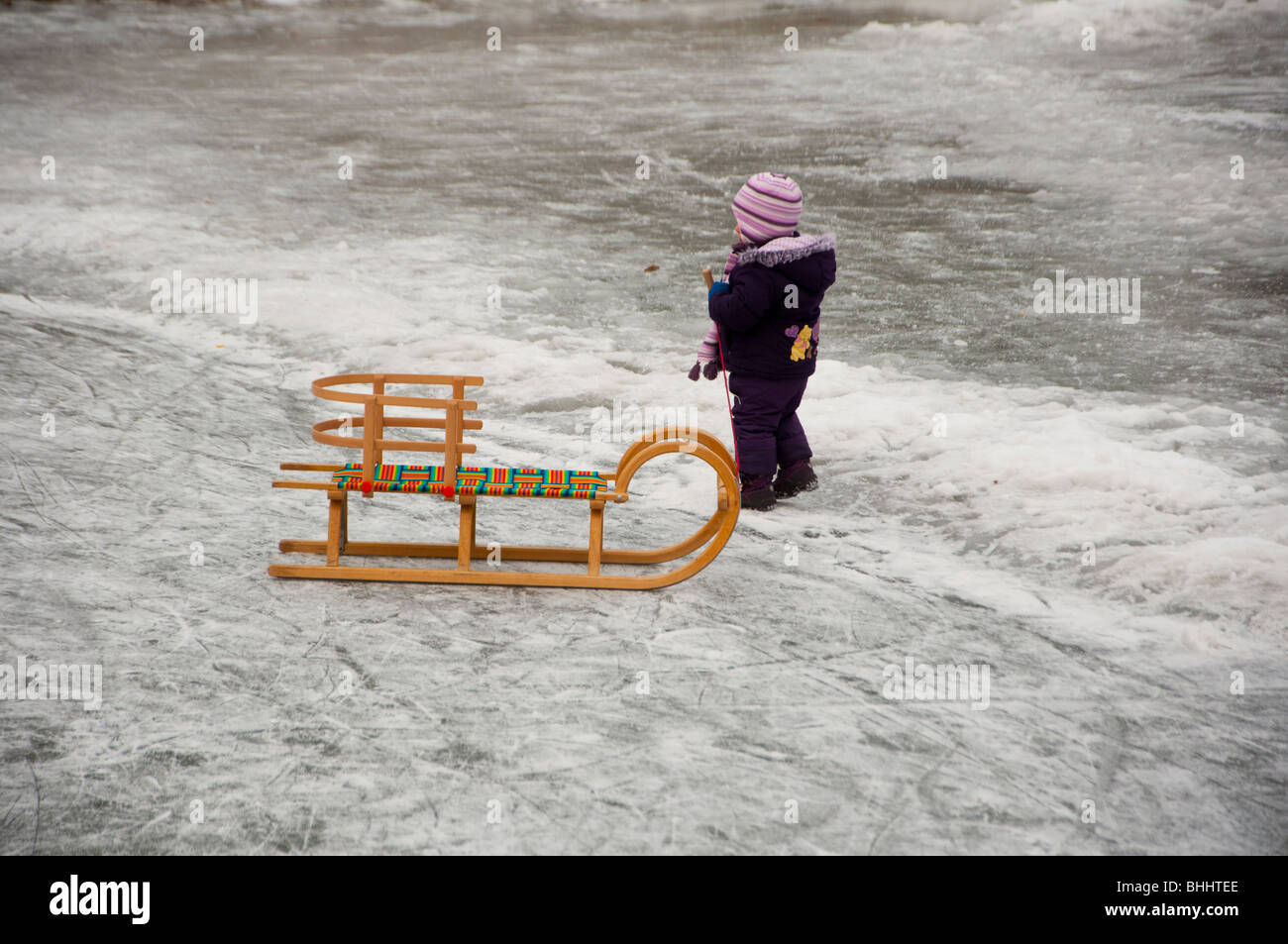 Little girl enjoying the frozen lake with her sledge Stock Photo - Alamy