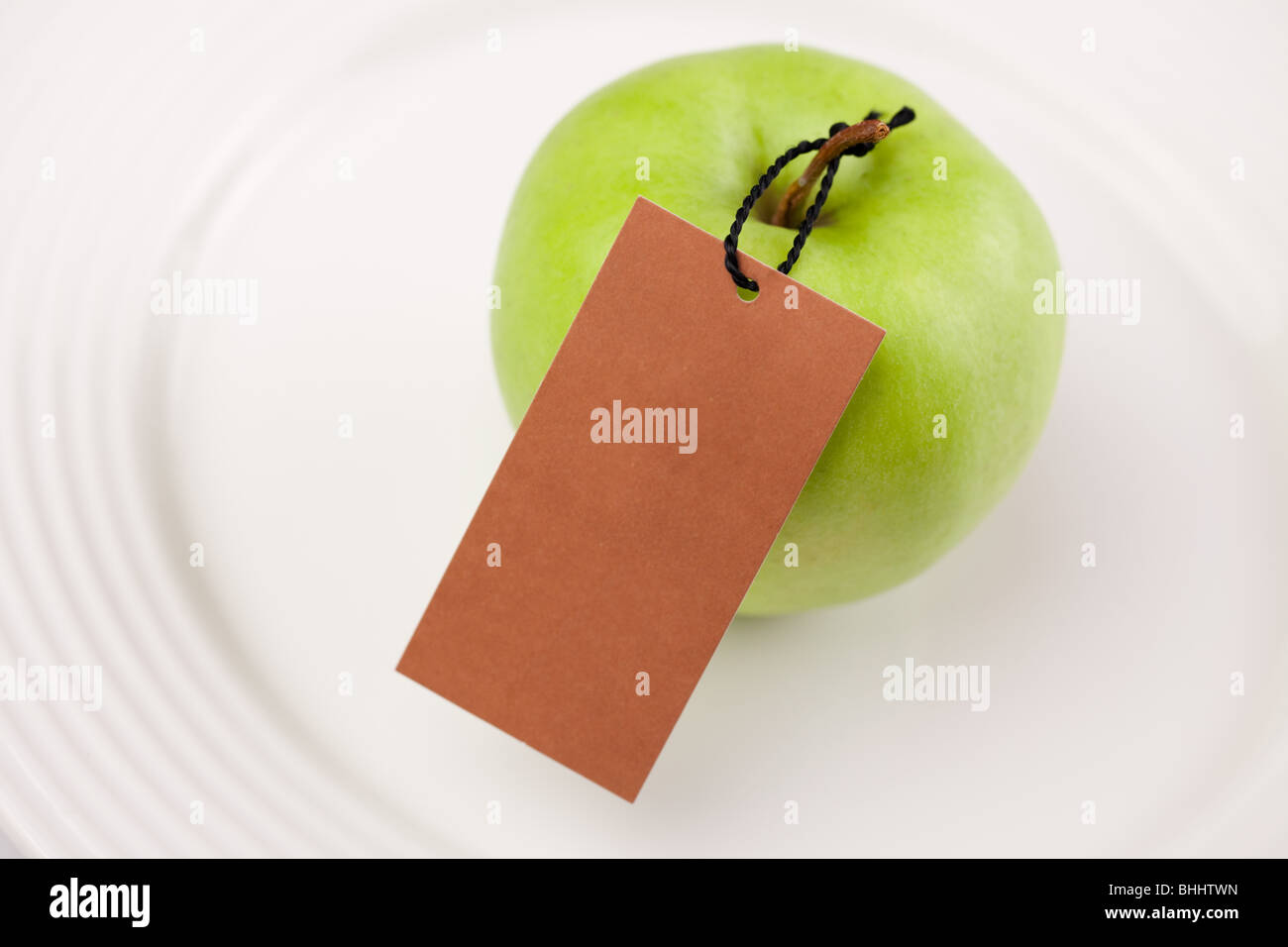 green apple with label on white plate Stock Photo - Alamy