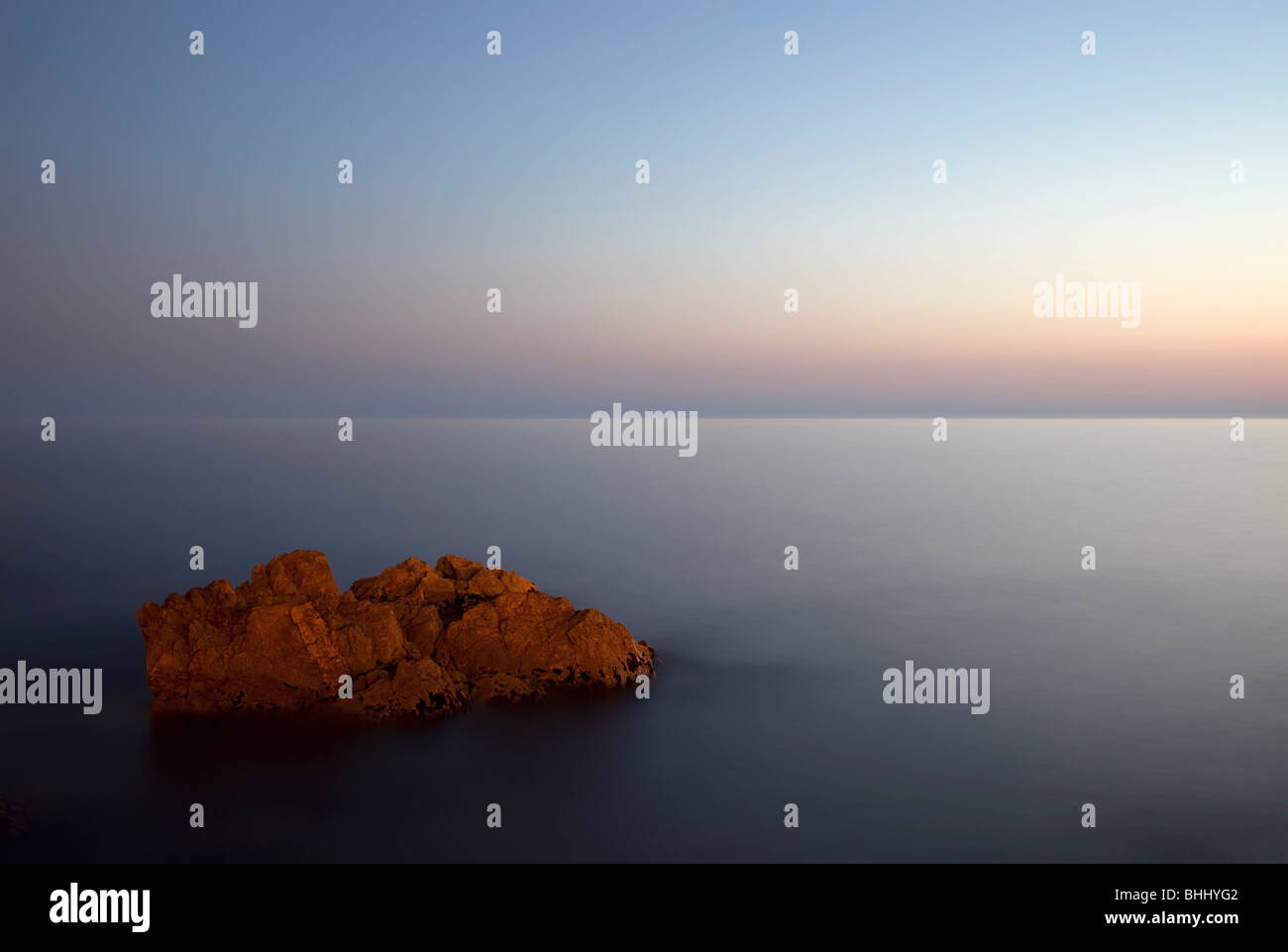 Rock in sea at sunset Stock Photo - Alamy