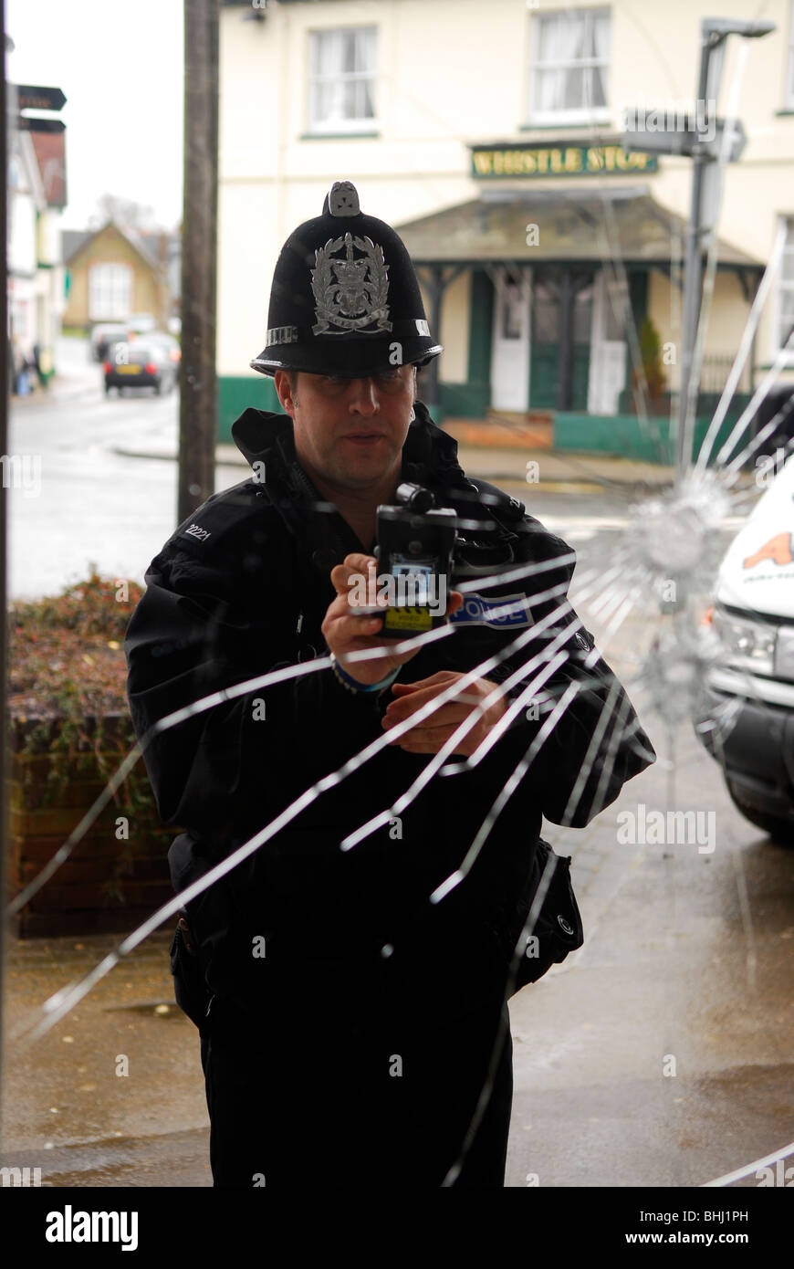 Police officer filming vandalised broken window for evidential purposes ...