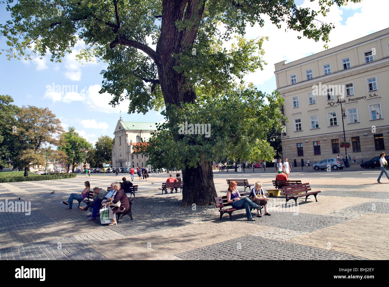 People sitting on benches in a typical Polish town square in summer ...