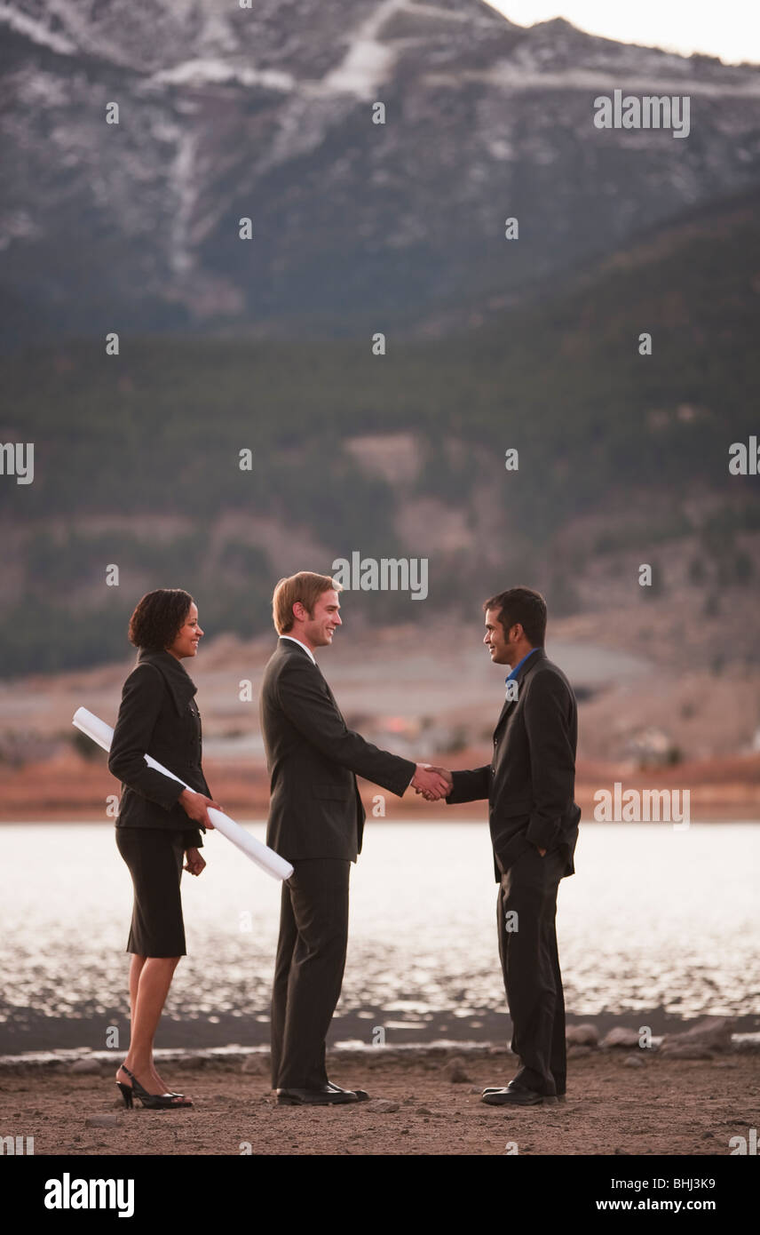 Couple with plans shakes hands with man Stock Photo - Alamy