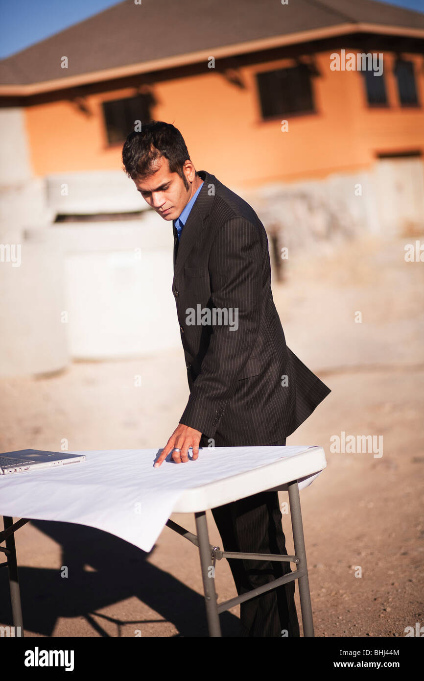 Man examining plans on worksite Stock Photo - Alamy