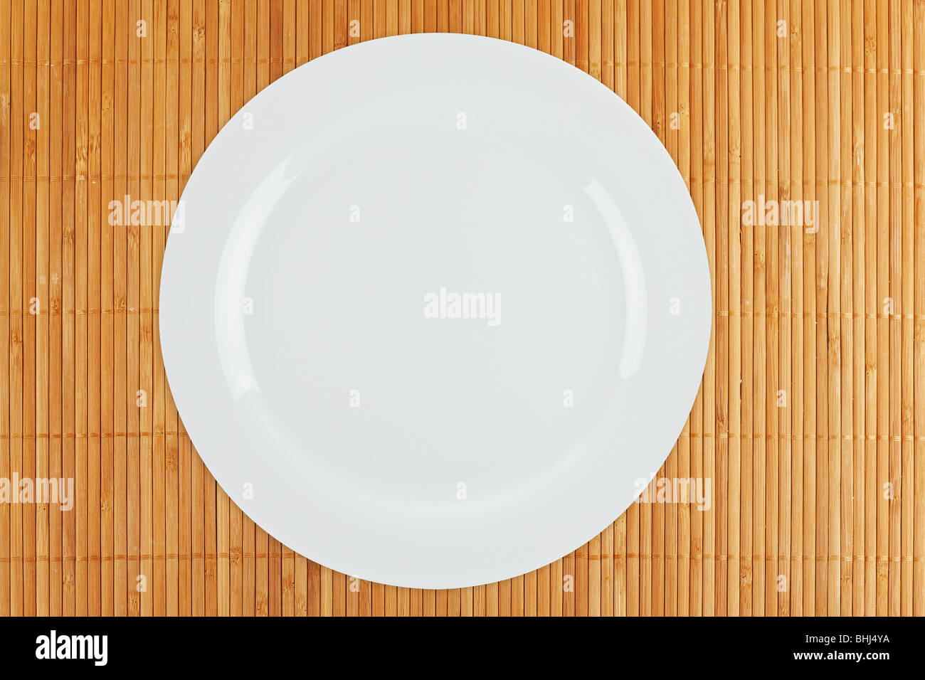 Empty dinner plate with soft shadow on bamboo mat Stock Photo - Alamy