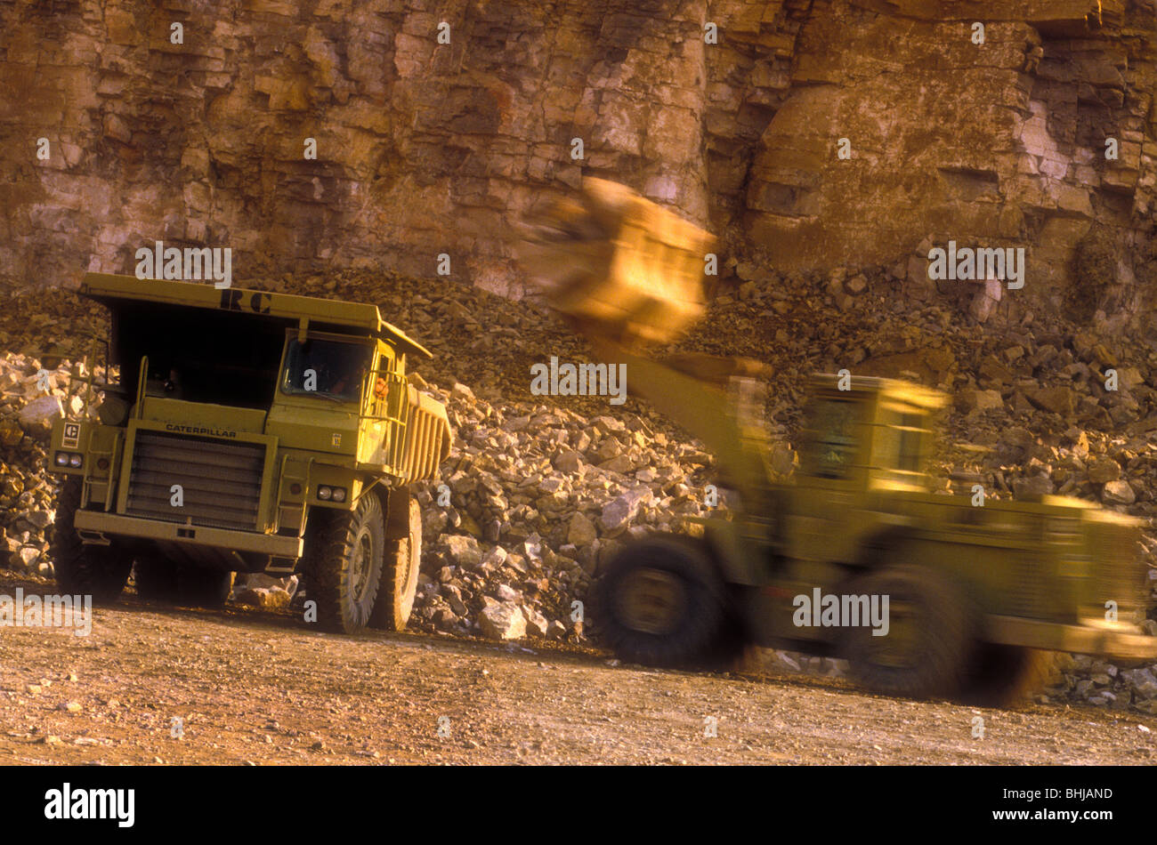 Giant Caterpillar quarry dump truck being filled by a front loader ...