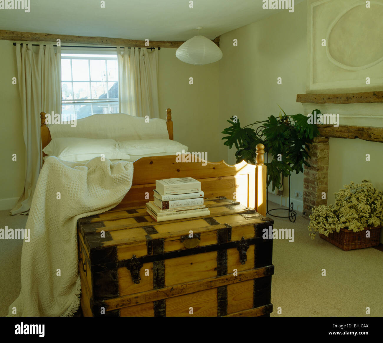 Large wooden chest below bed with white bedlinen and cream throw in ...
