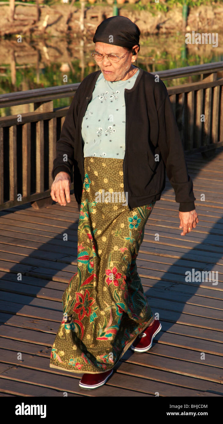 Myanmar, Burma, Yangon, Rangoon, old lady walking around Kandawgyi Lake ...