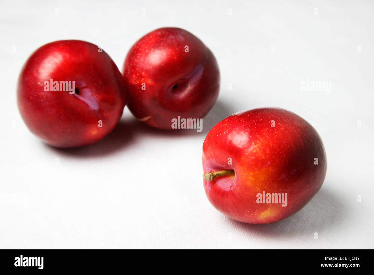 Three Red Plums on a White Background Stock Photo - Alamy