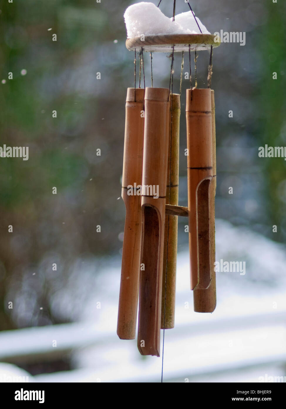 bamboo wind chimes hanging from roof in garden in winter with snow ...