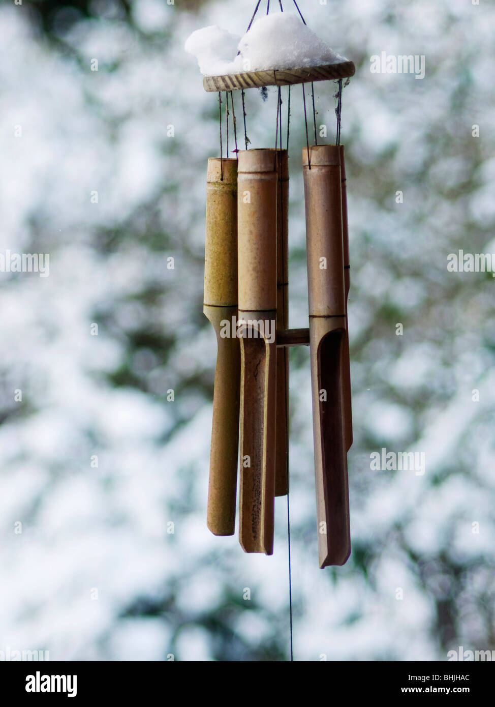 bamboo wind chimes hanging from roof in garden in winter with snow ...