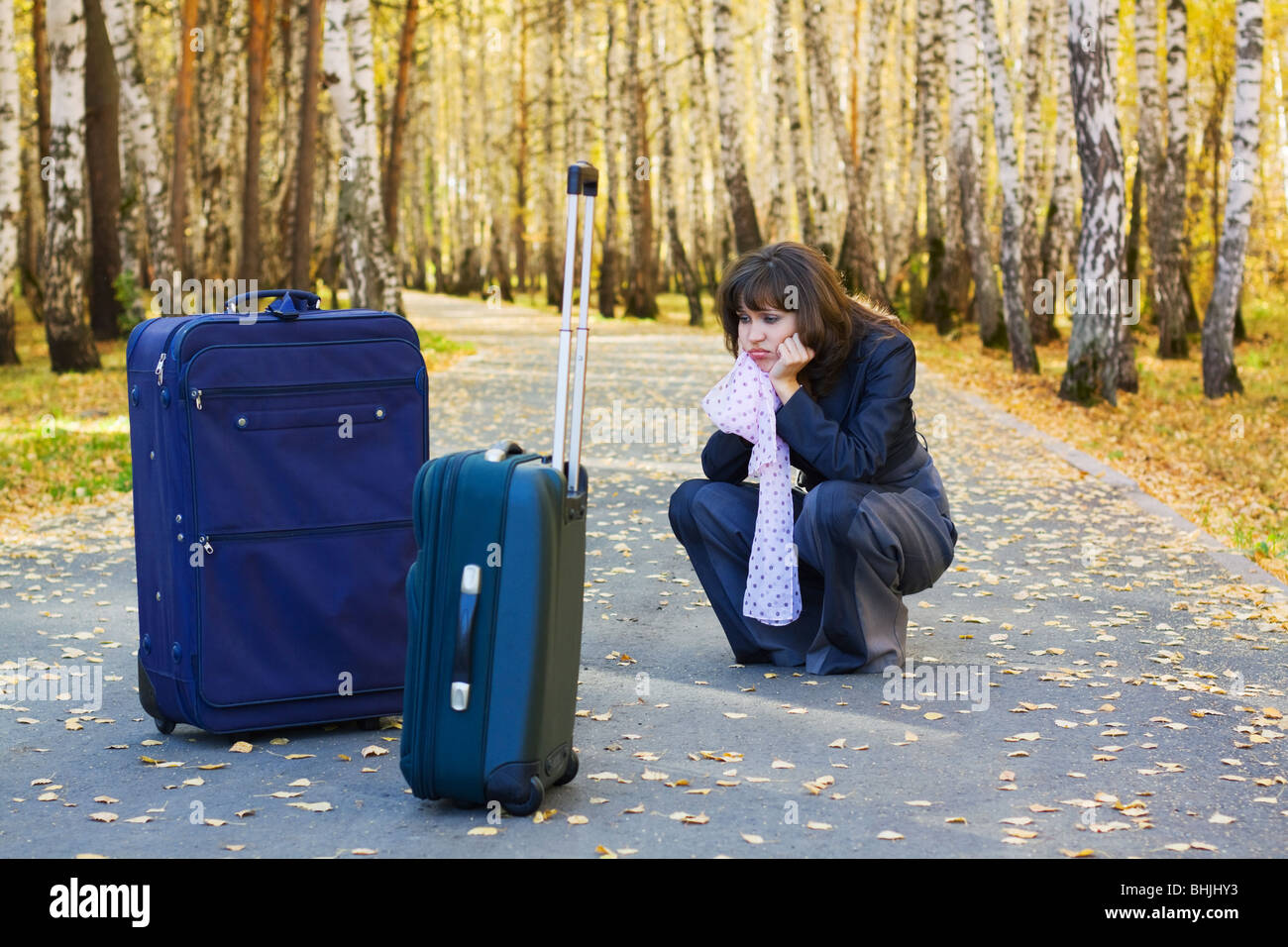 Sad young businesswoman with a luggage sitting on the road Stock Photo ...