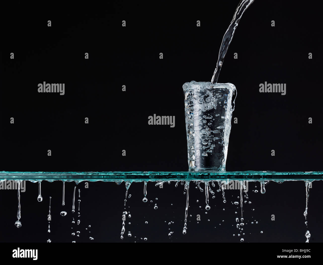 Pouring water into a glass, Overflowing Stock Photo - Alamy