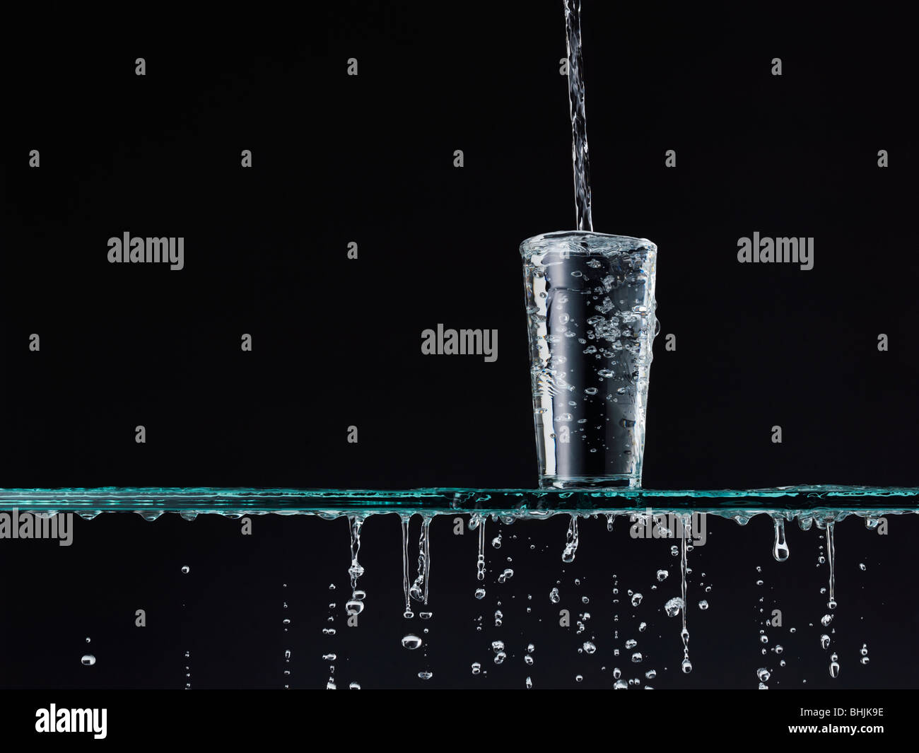 Pouring water into a glass, Overflowing Stock Photo - Alamy