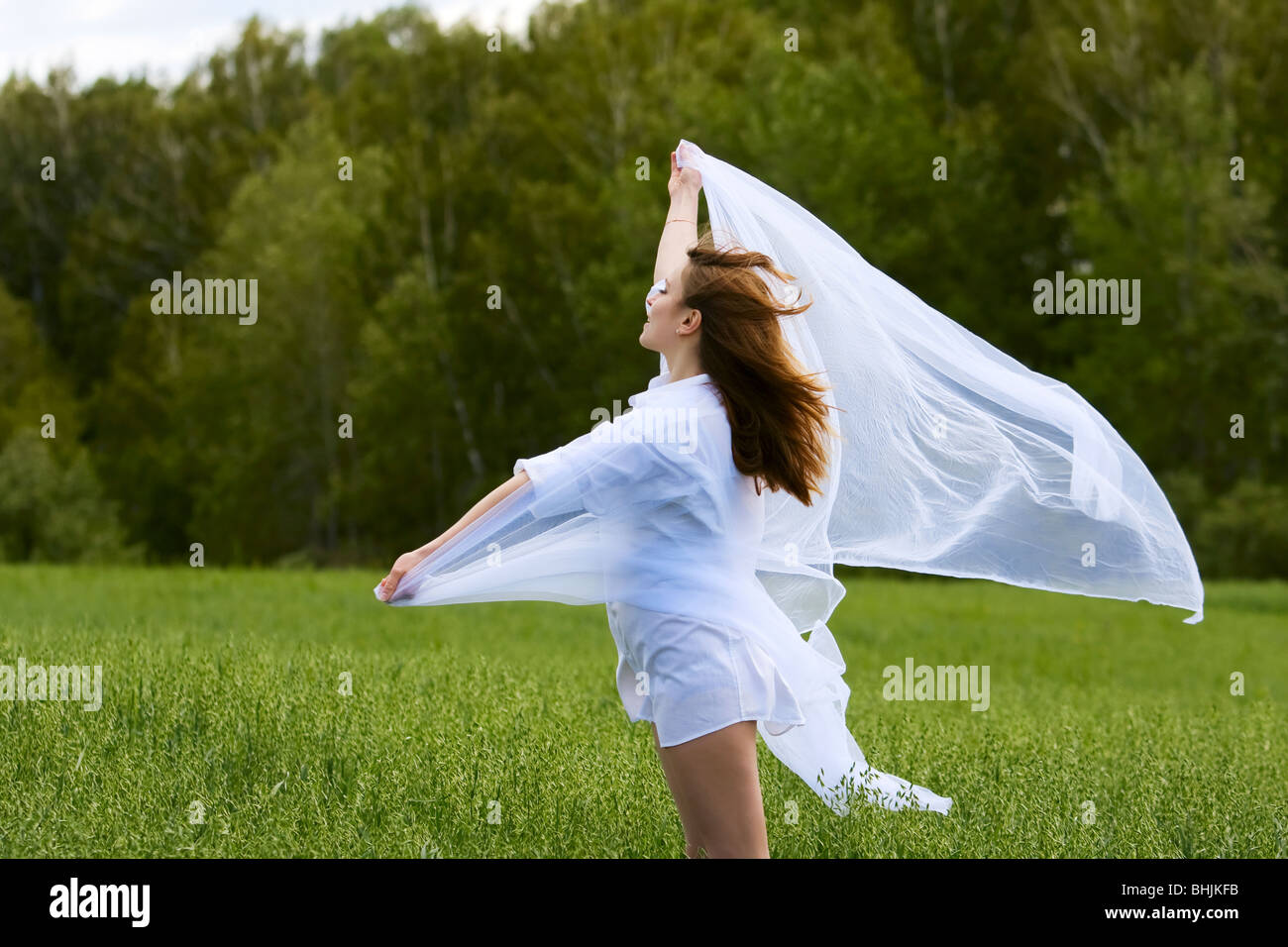 Happy young woman walking in a field Stock Photo - Alamy