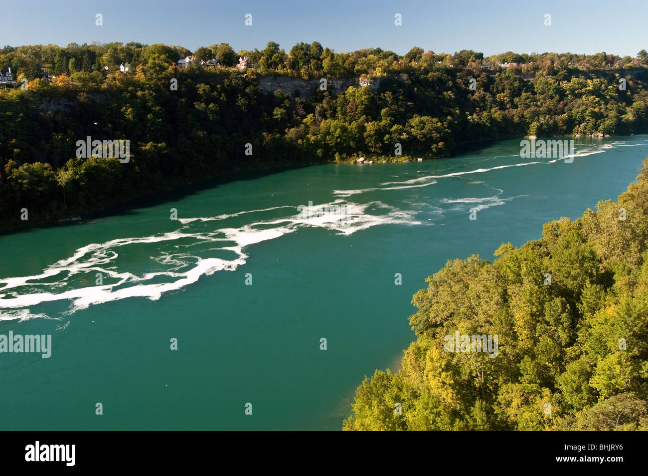Niagara river after Niagara Falls with green trees on both American and ...
