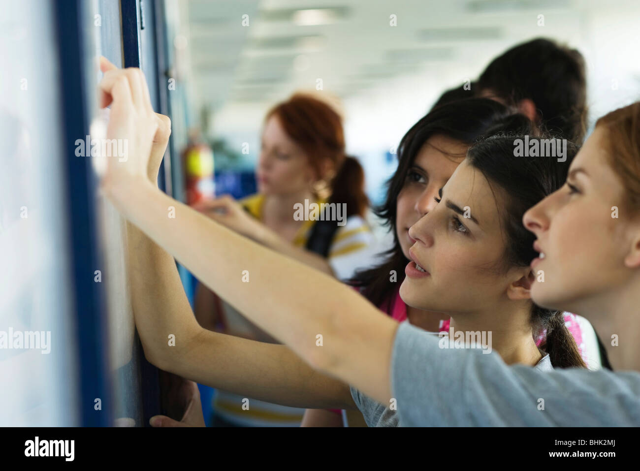 Female high school students looking at bulletin board Stock Photo - Alamy