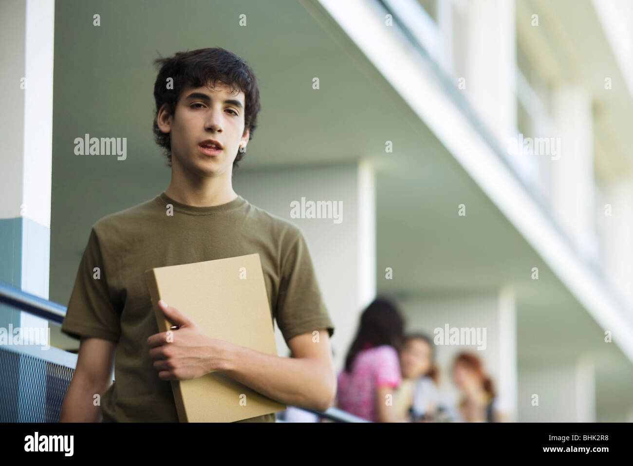 Male high school student carrying binder under arm Stock Photo - Alamy