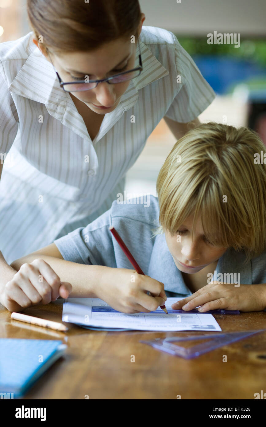 Teacher looking over student's shoulder reviewing their classwork Stock ...