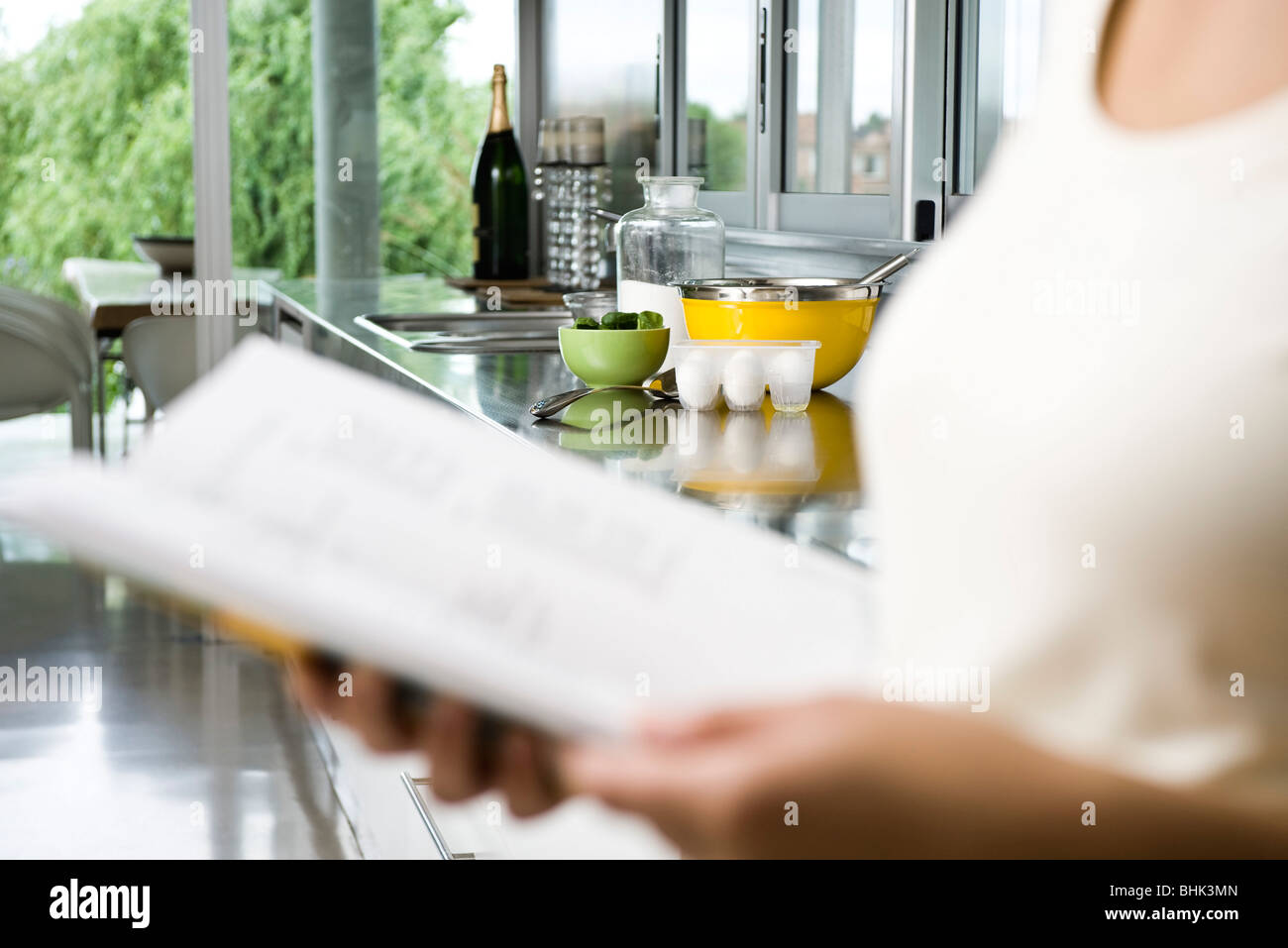 Reading recipe in cookbook, ingredients on kitchen counter in ...