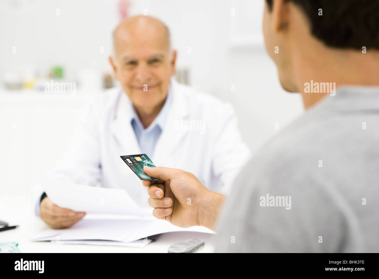 Patient handing credit card to doctor Stock Photo - Alamy