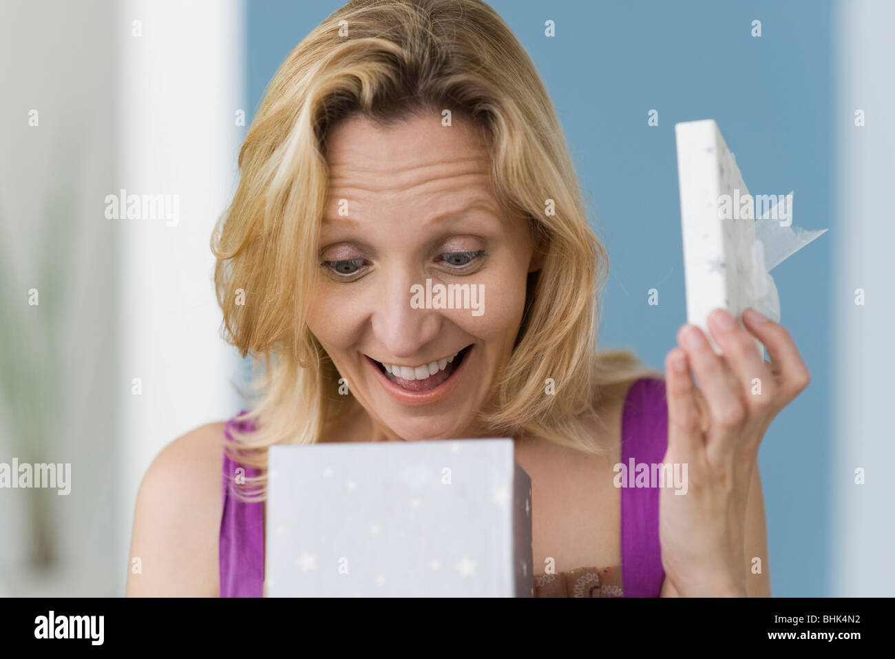 Woman with look of surprise opening gift Stock Photo - Alamy