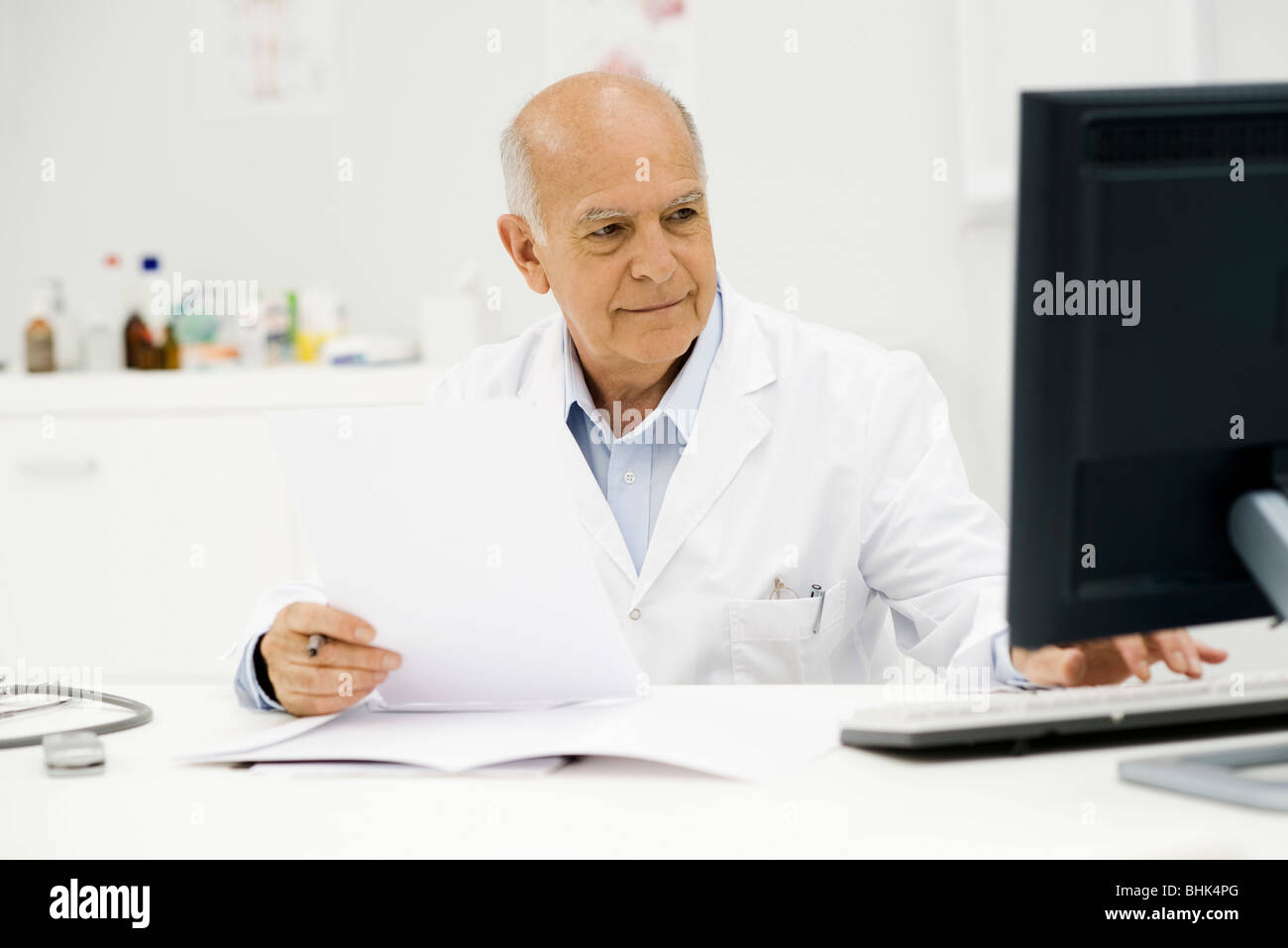 Doctor at desk completing paperwork Stock Photo - Alamy
