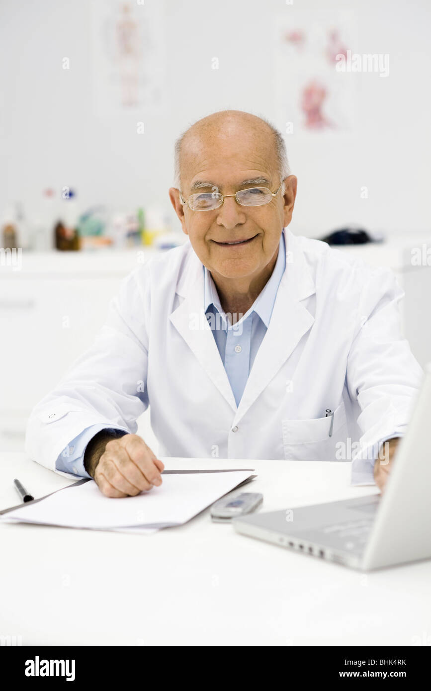 Doctor at desk completing paperwork Stock Photo - Alamy