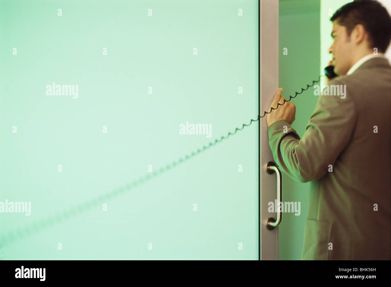 Businessman talking on landline phone, rear view Stock Photo - Alamy