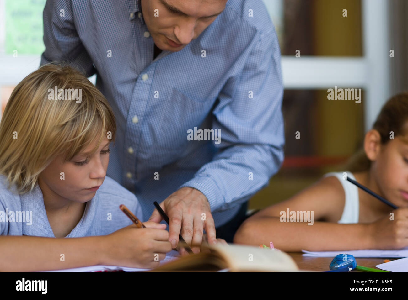 Teacher helping elementary school student in class Stock Photo - Alamy