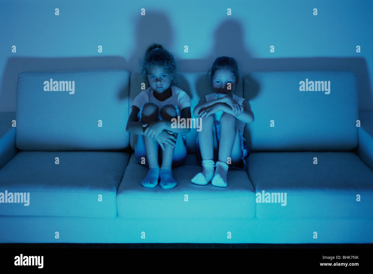 Two girls watching TV together on sofa at night Stock Photo - Alamy