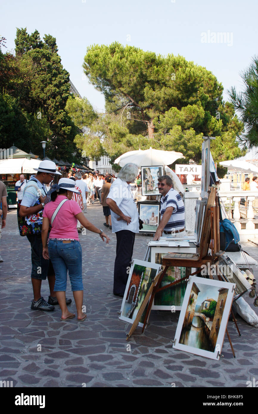 Street artist in Venice offering paintings of local scenes of the city ...