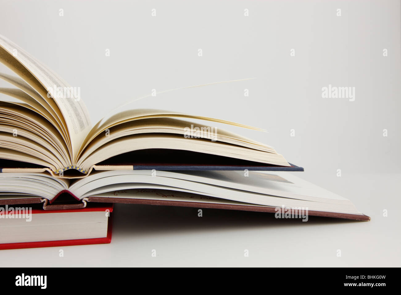 Two open books on a third closed book with a white background Stock ...