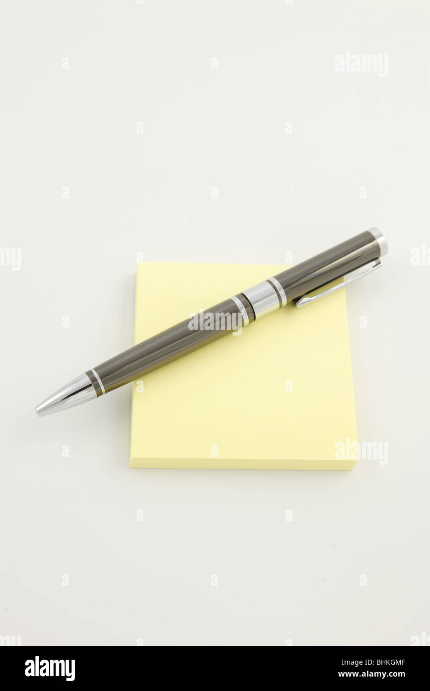 Pen on a yellow sticky note pad Stock Photo - Alamy