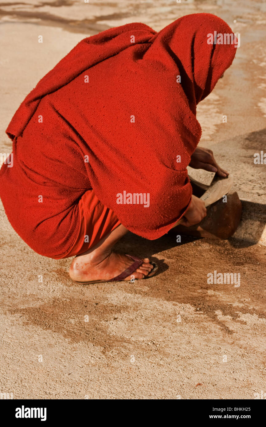 Saffron robed burmese monk sharpening knife in Myanmar (Brma Stock ...
